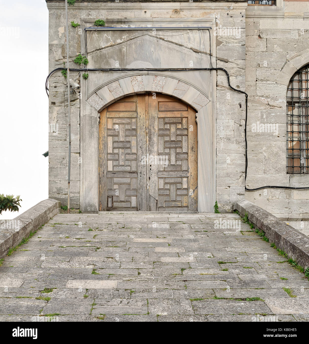 Stone tiled ramp leading to a wooden aged door over a stone wall of one ...