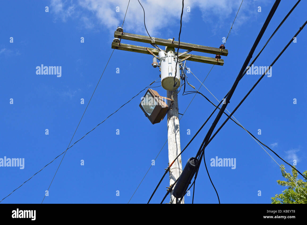 Towering telephone pole with cables, wires, and a street light on a ...