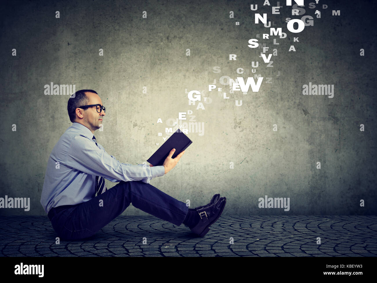 Mature man reading a book with alphabet letters coming out of the book ...