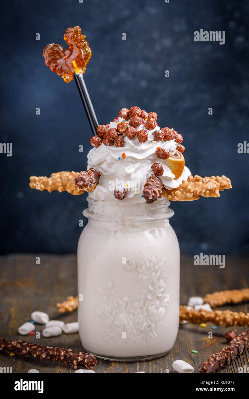 Unusual milkshake decorated with candies, marshmallows, whipped cream ...