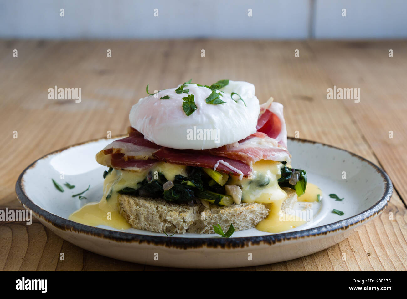 rustic tasty eggs benedict on plate on wooden table Stock Photo - Alamy