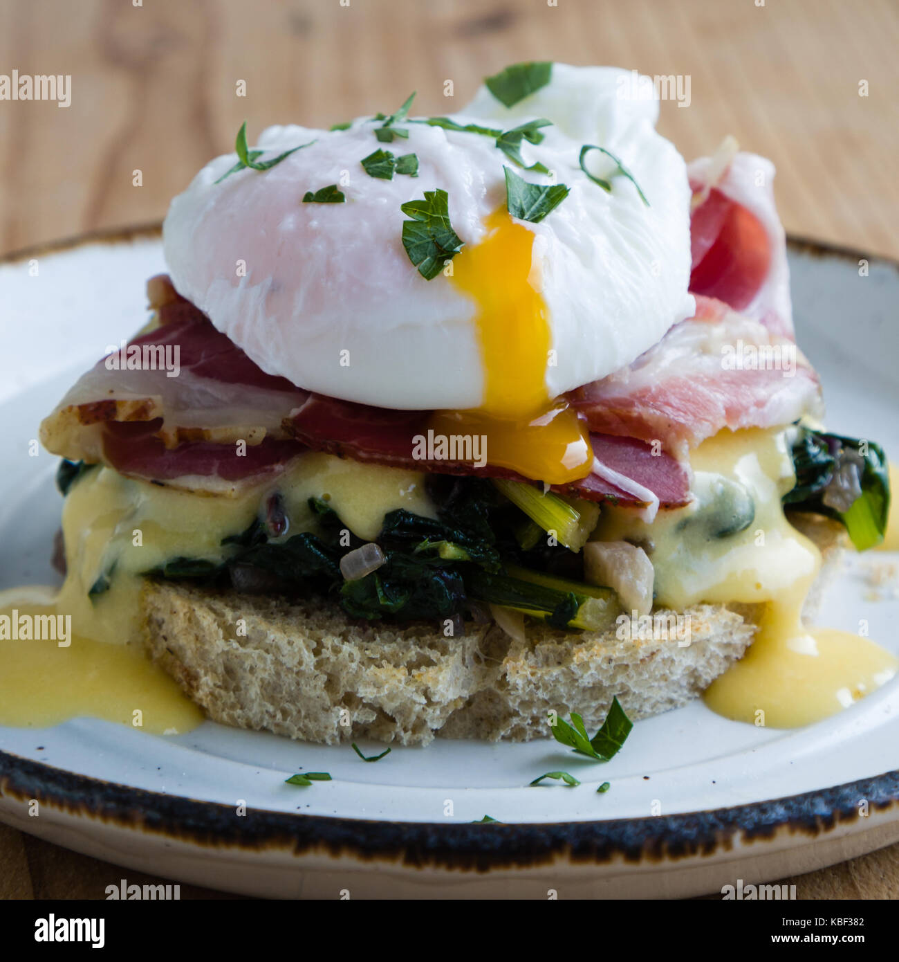 rustic tasty eggs benedict on plate on wooden table Stock Photo - Alamy