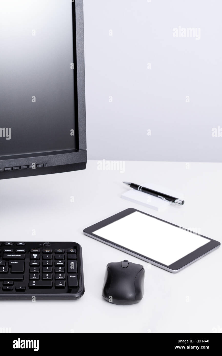 Tablet laying on desktop near pc monitor and keyboard in workplace ...