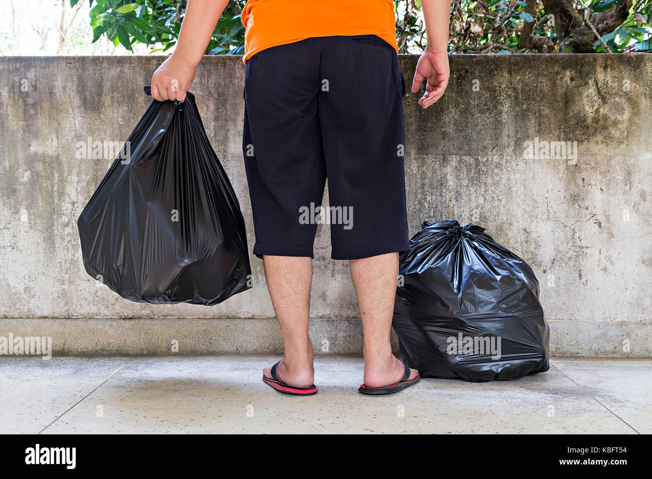 Low section of a young man carrying garbage bag Stock Photo - Alamy