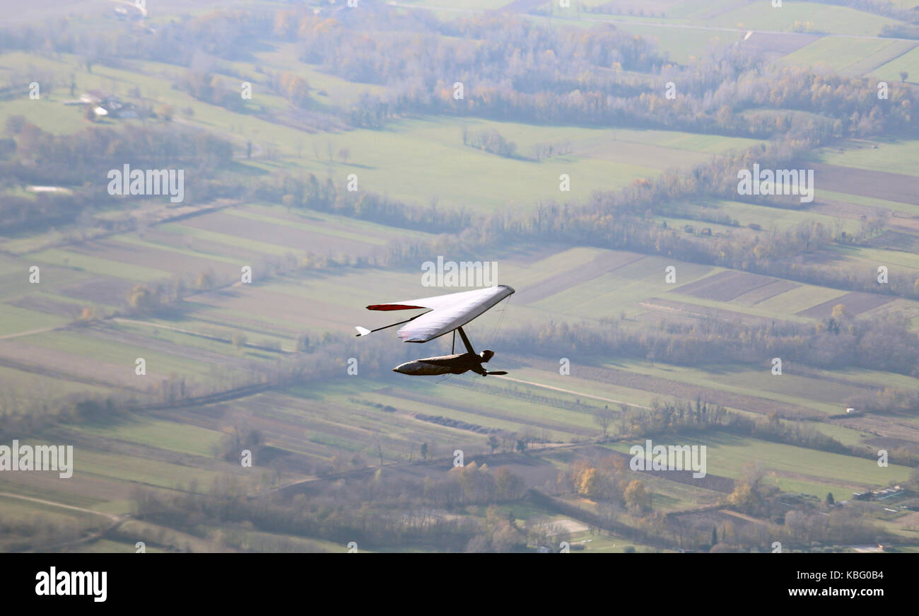 man flying high with hang glider above the plain. This is extreme sport ...
