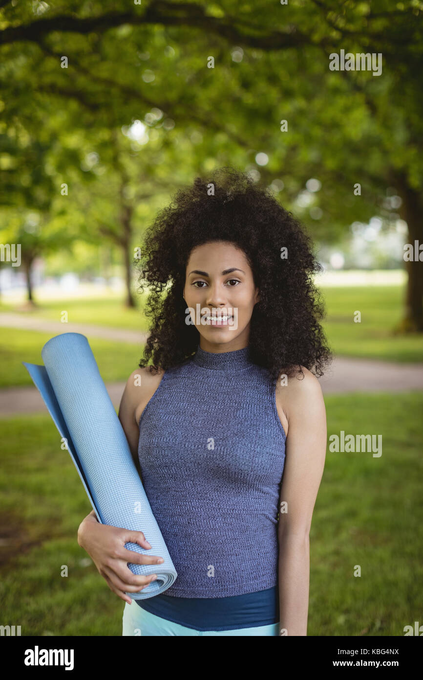Portrait of woman holding exercise mat in the park Stock Photo - Alamy