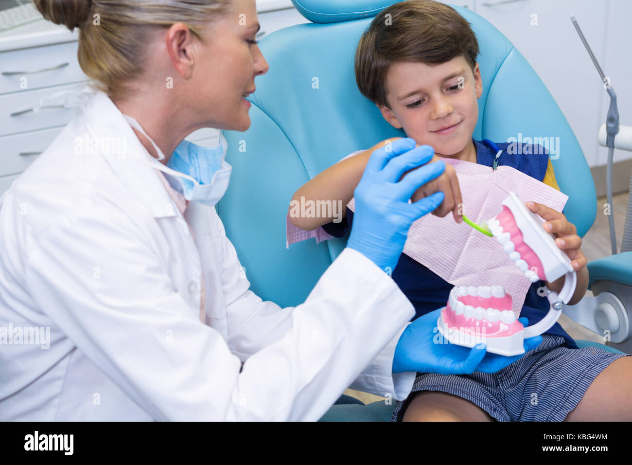 Dentist looking at boy brushing dentures at clinic Stock Photo - Alamy
