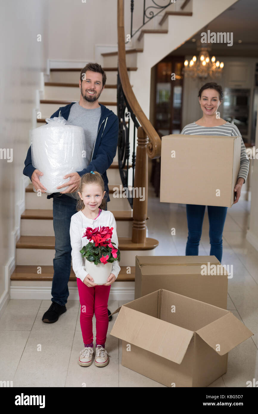 Parents and daughter opening cardboard boxes in living room at home ...