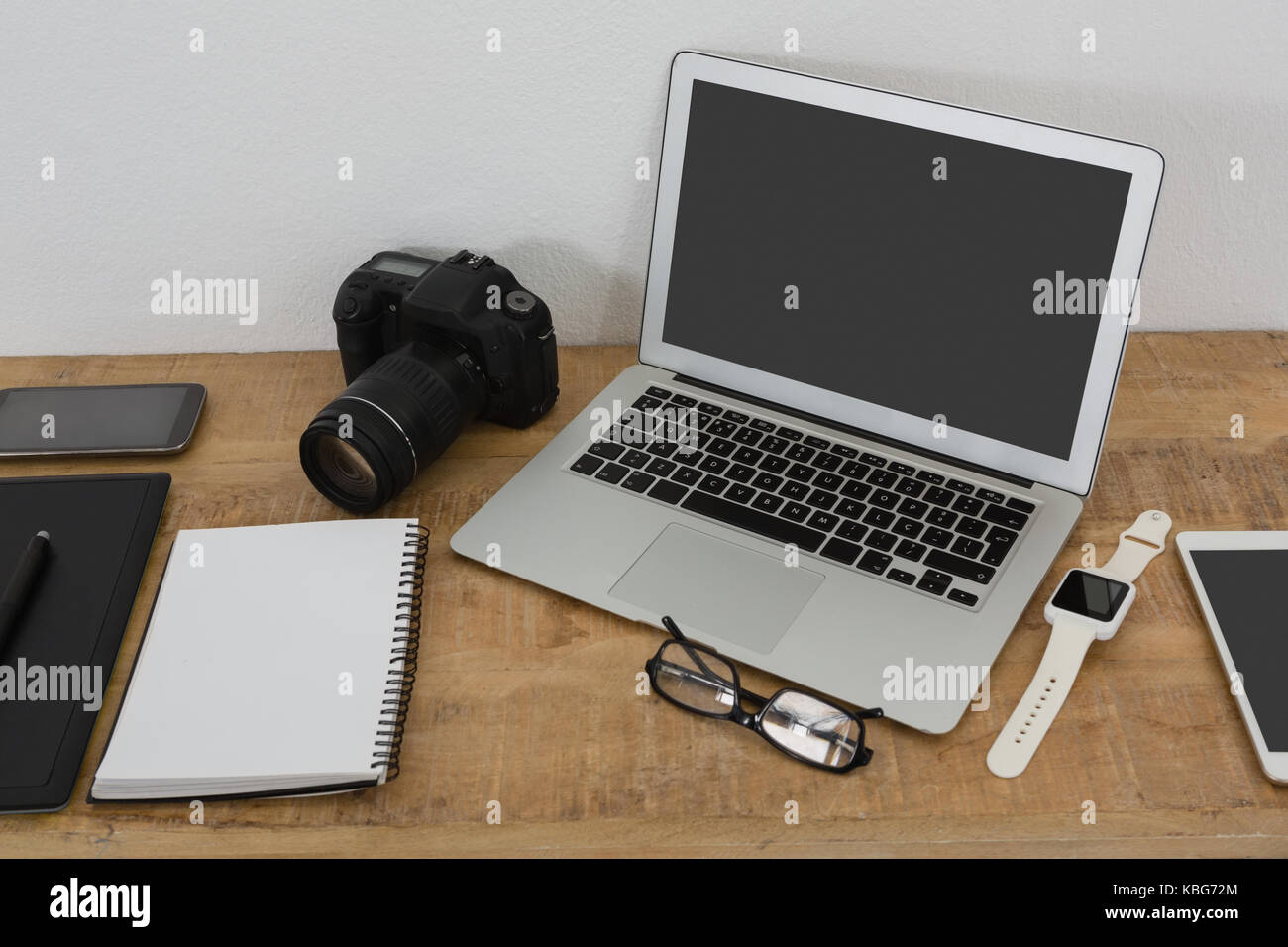 Close-up of laptop, wristwatch, notepad, camera and mobile phone on ...