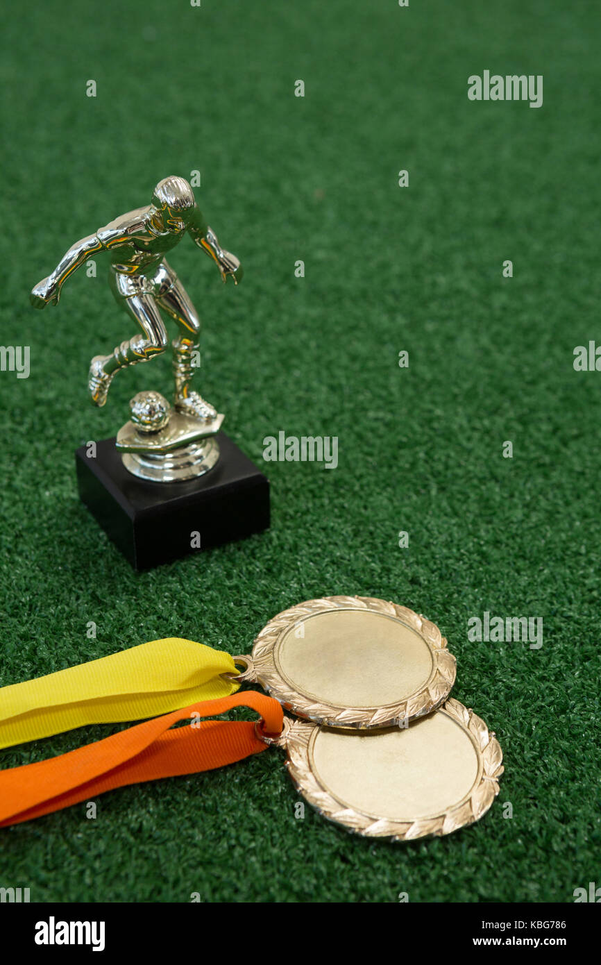 Close-up of trophy and medals on artificial grass Stock Photo - Alamy