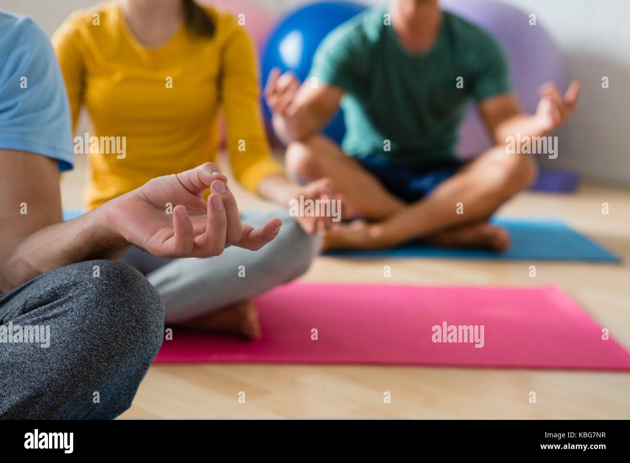 Midsection of yoga instructor with students meditating in lotus ...