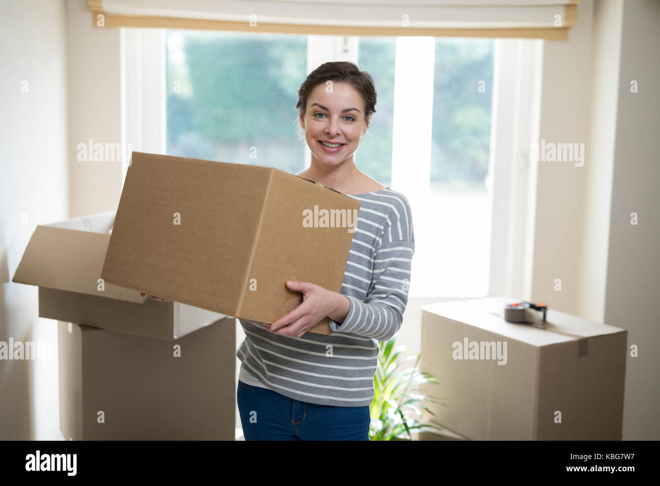 Woman carrying cardboard boxes in living room at home Stock Photo - Alamy
