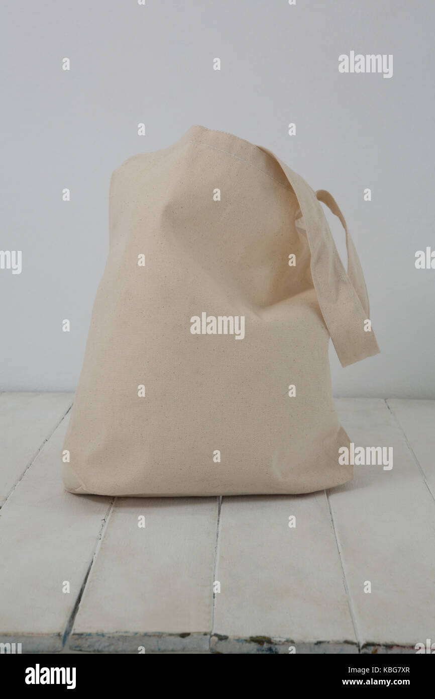 Beige bag on table against white wall Stock Photo - Alamy