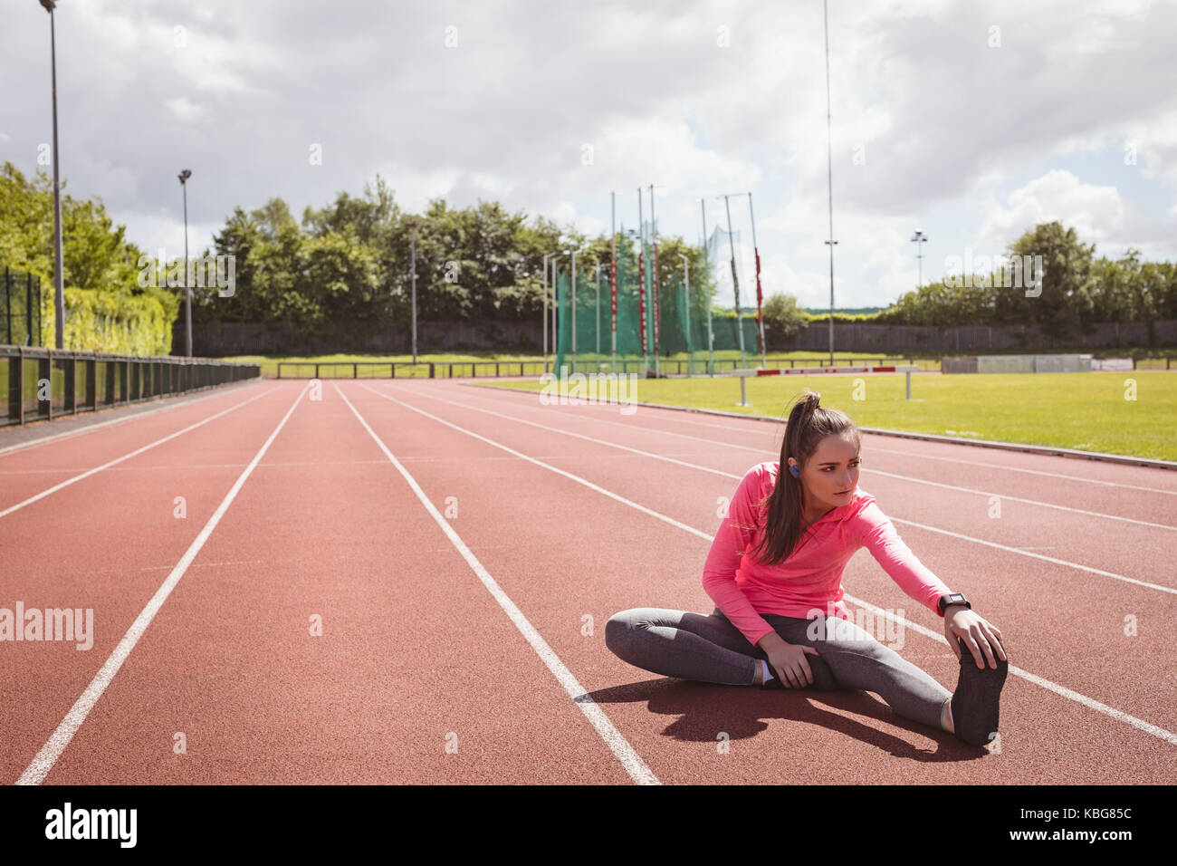 Young woman performing stretching exercise on a race track Stock Photo ...
