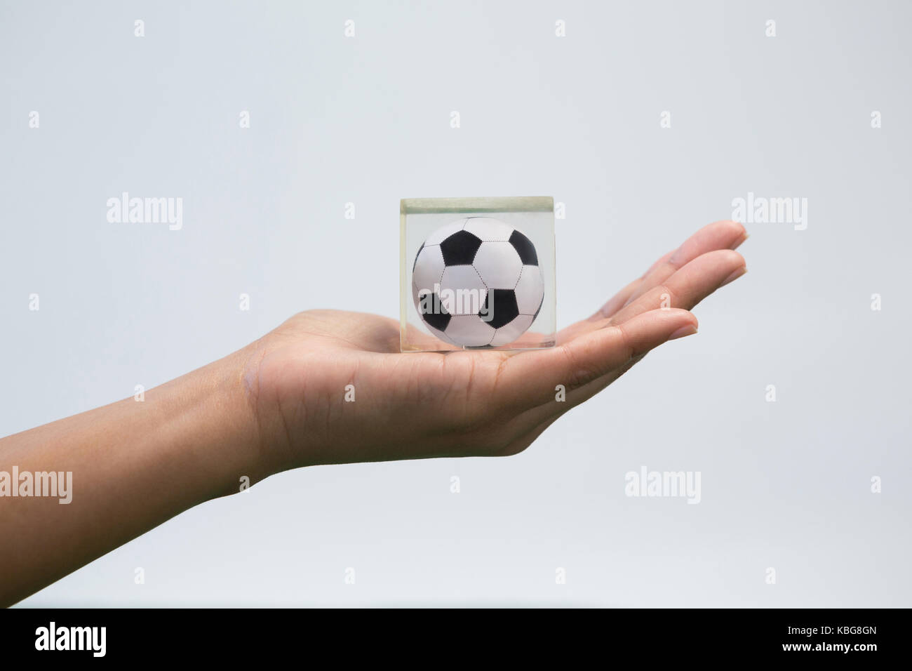 Close-up of hand holding acrylic football cube against white background ...