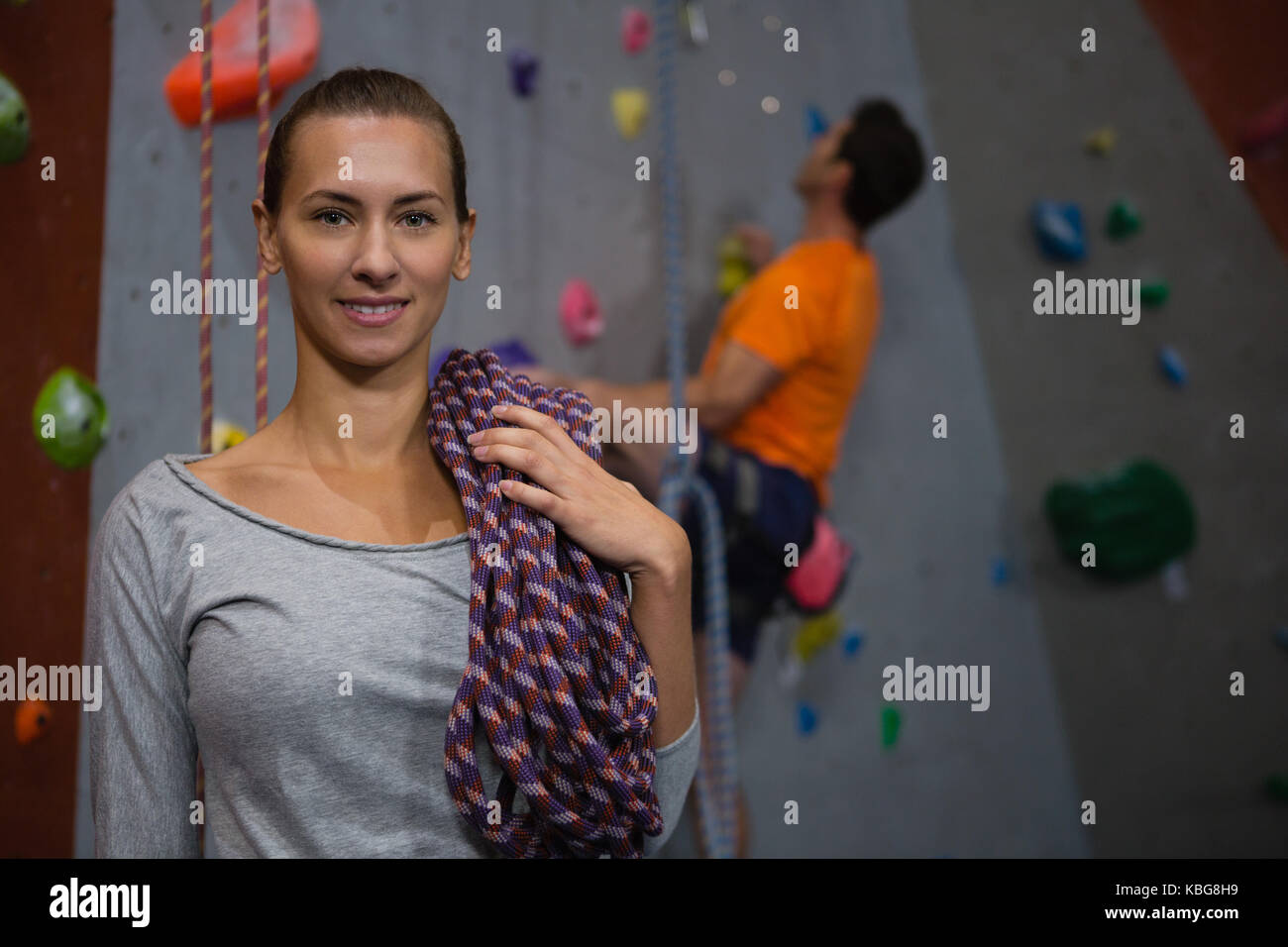 Portrait of female athlete carrying rope while standing against man ...