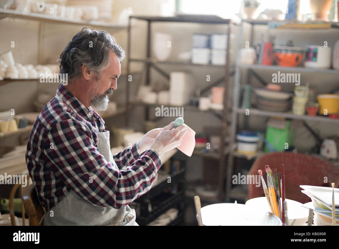 Male potter painting bowl in pottery workshop Stock Photo - Alamy