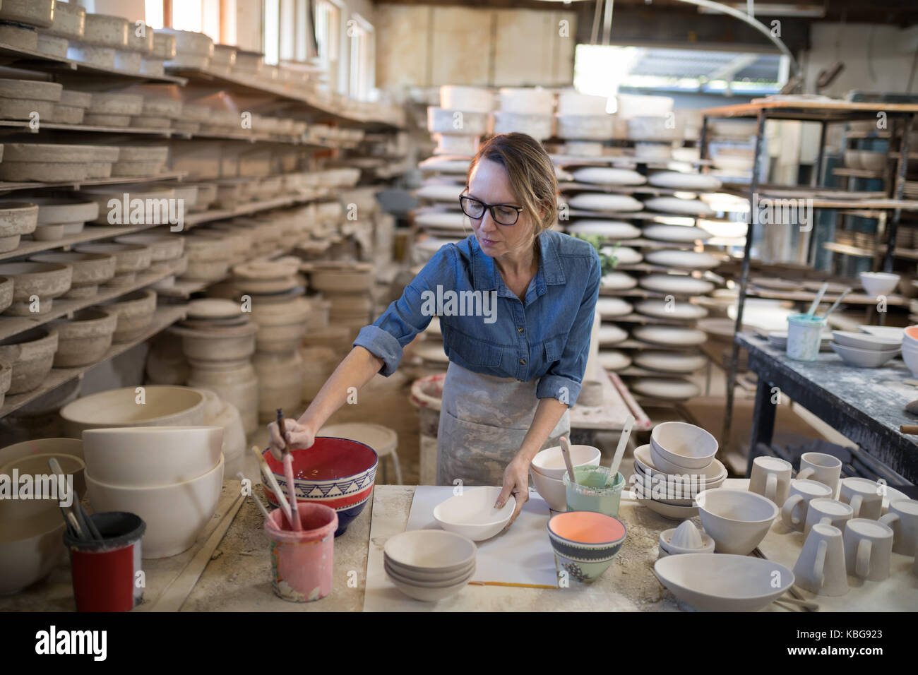 Female potter painting bowl in pottery workshop Stock Photo - Alamy
