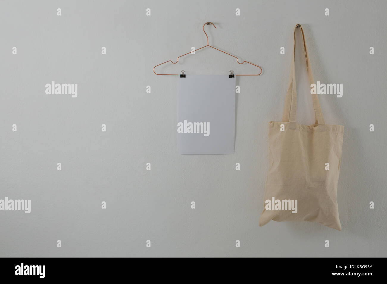 Close-up of paper and bag hanging against white wall Stock Photo - Alamy