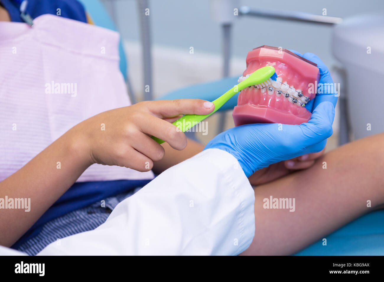Cropped image of dentist teaching boy brushing teeth of dentures at ...