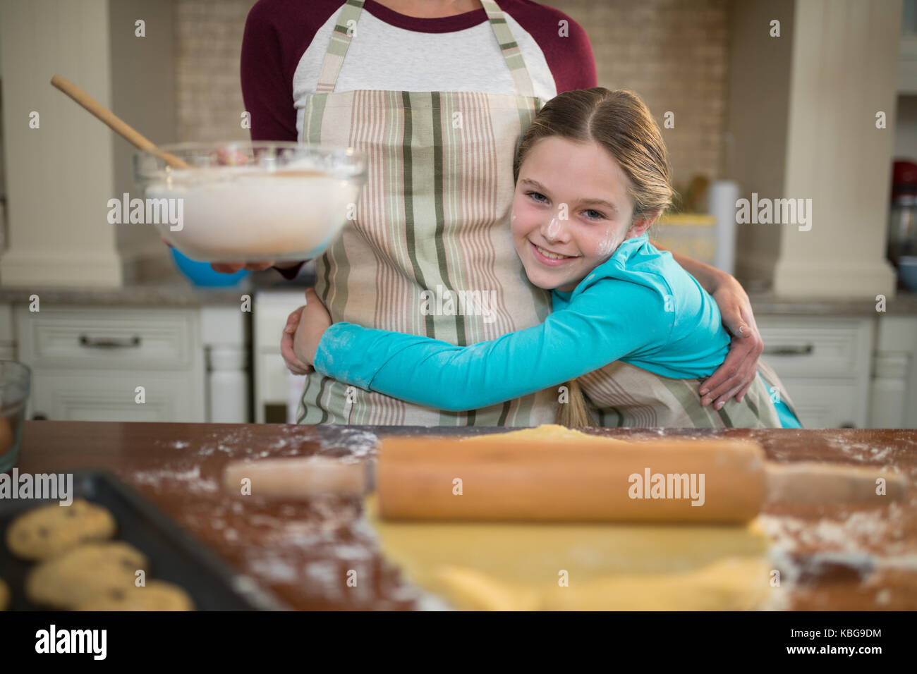 Happy daughter hugging mother while preparing cookies in kitchen Stock ...