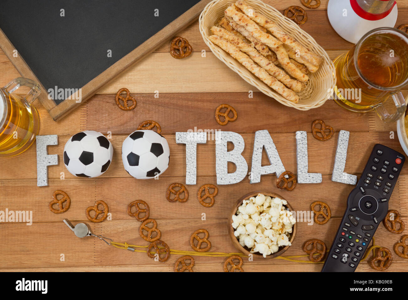 Overhead of remote control, slate, snacks, drinks and football word ...