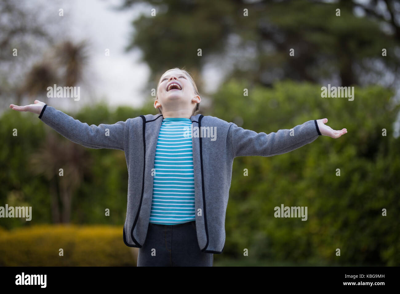 Young girl standing in the park with arms wide open Stock Photo - Alamy
