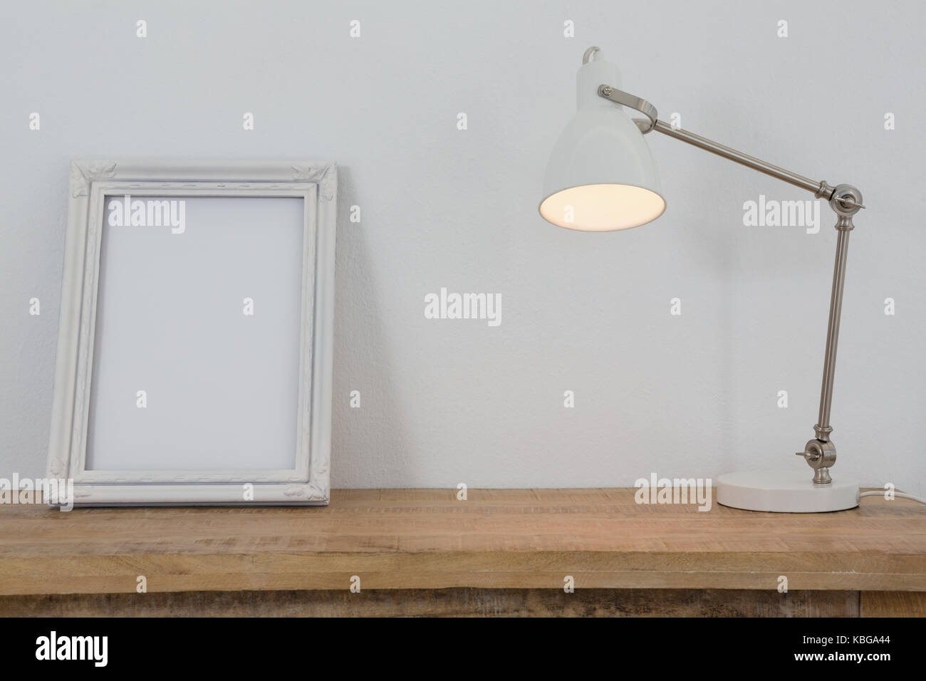 Picture frame and illuminated lamp on wooden table Stock Photo - Alamy