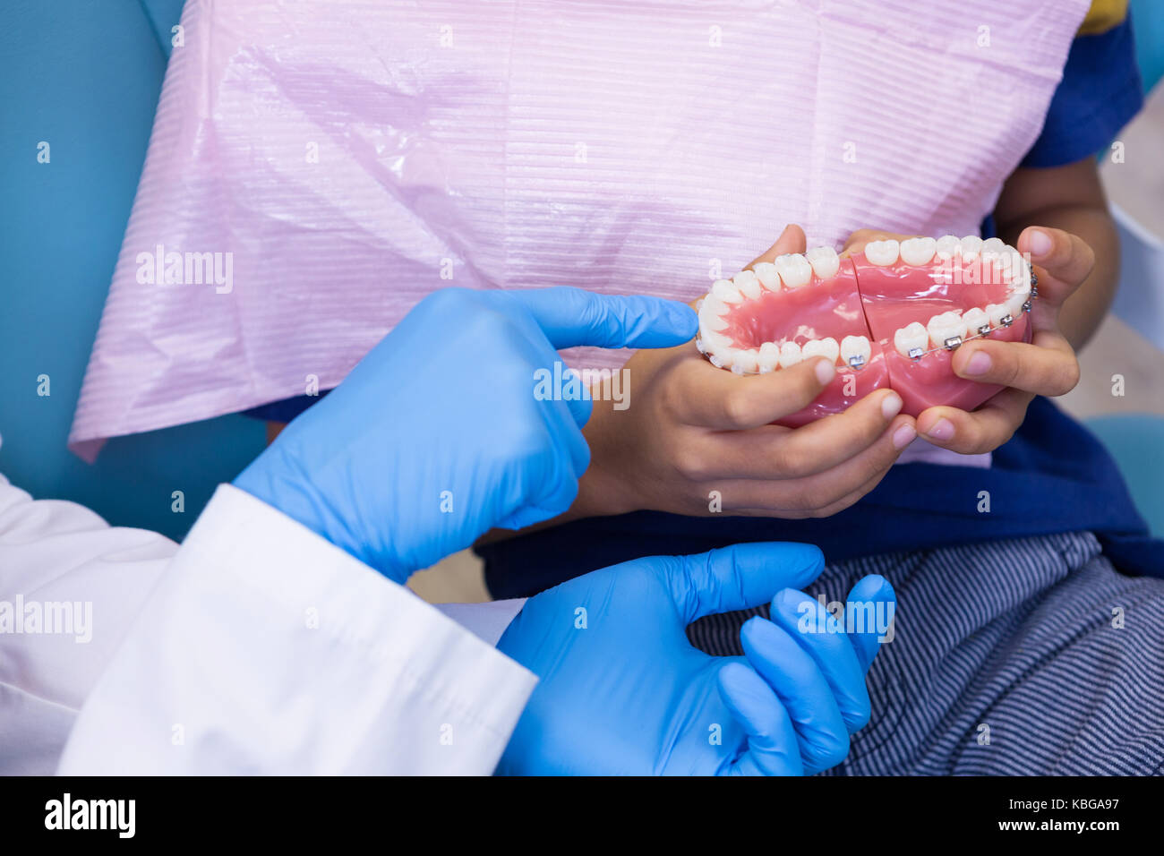 Cropped image of dentist showing dentures to boy at medical clinic ...
