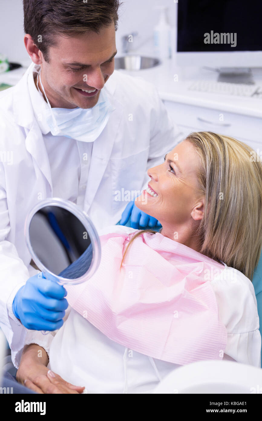 Dentist showing mirror to happy patient at dental clinic Stock Photo ...