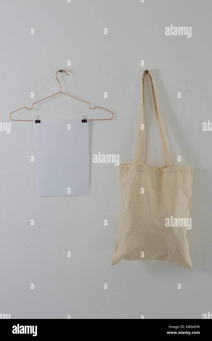 Close-up of paper and bag hanging against white wall Stock Photo - Alamy