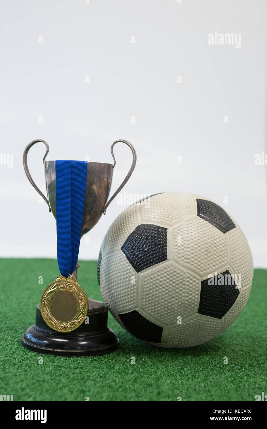 Close-up of football, trophy and medal on artificial grass against ...