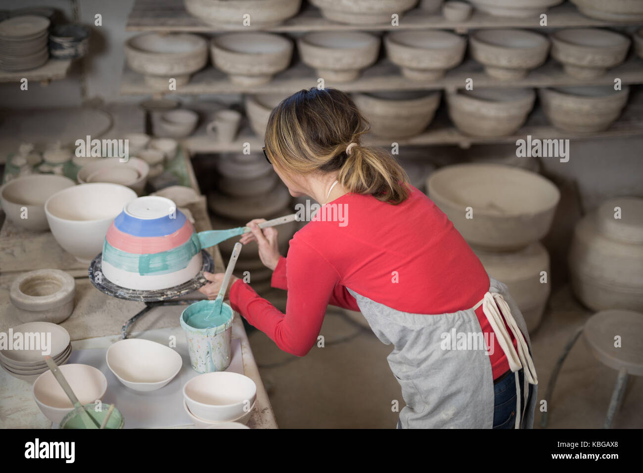 Female potter painting bowl in pottery workshop Stock Photo - Alamy