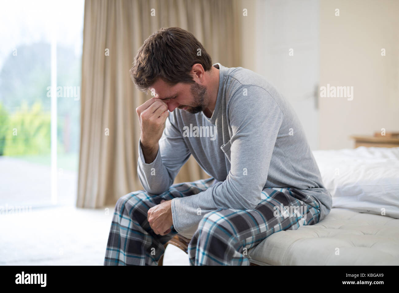 Stressed man sitting on the bed at home Stock Photo - Alamy
