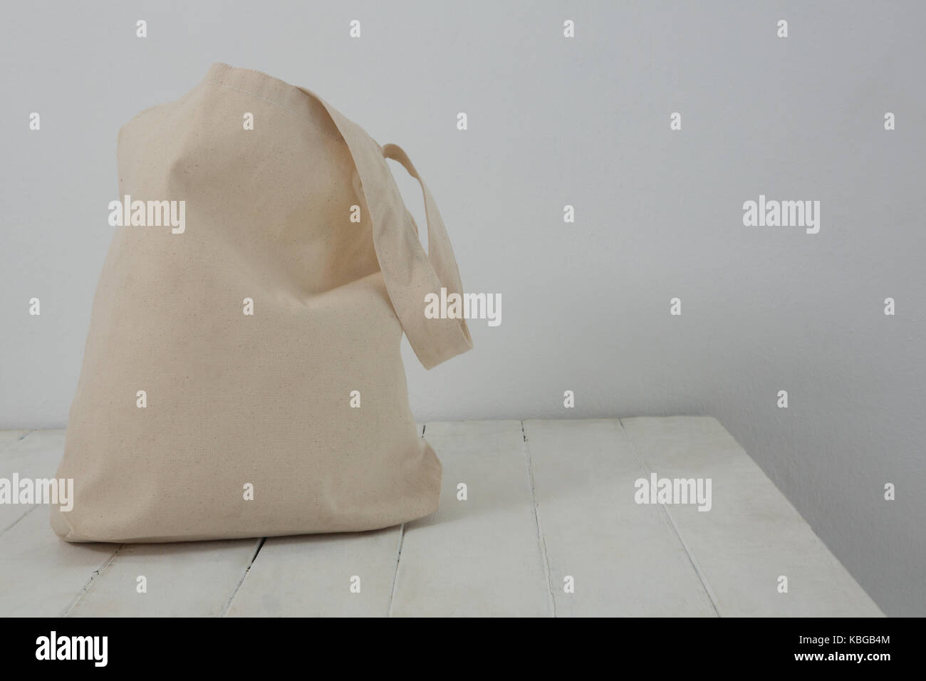 Beige bag on table against white wall Stock Photo - Alamy