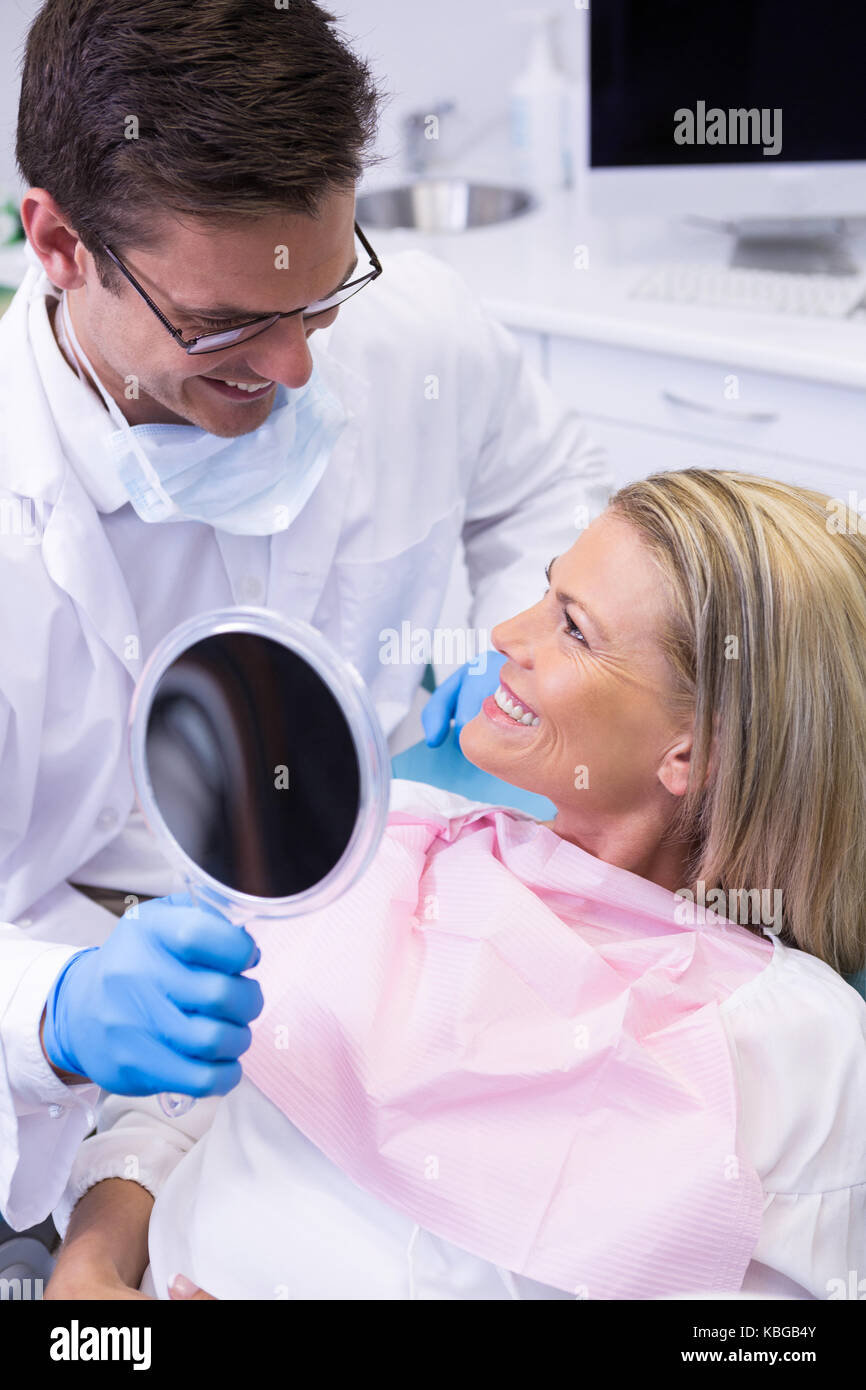Doctor showing mirror to happy patient at dental clinic Stock Photo - Alamy