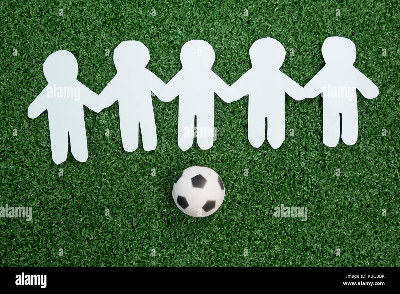 Close-up of paper cut outs and footballs arranged on artificial grass ...