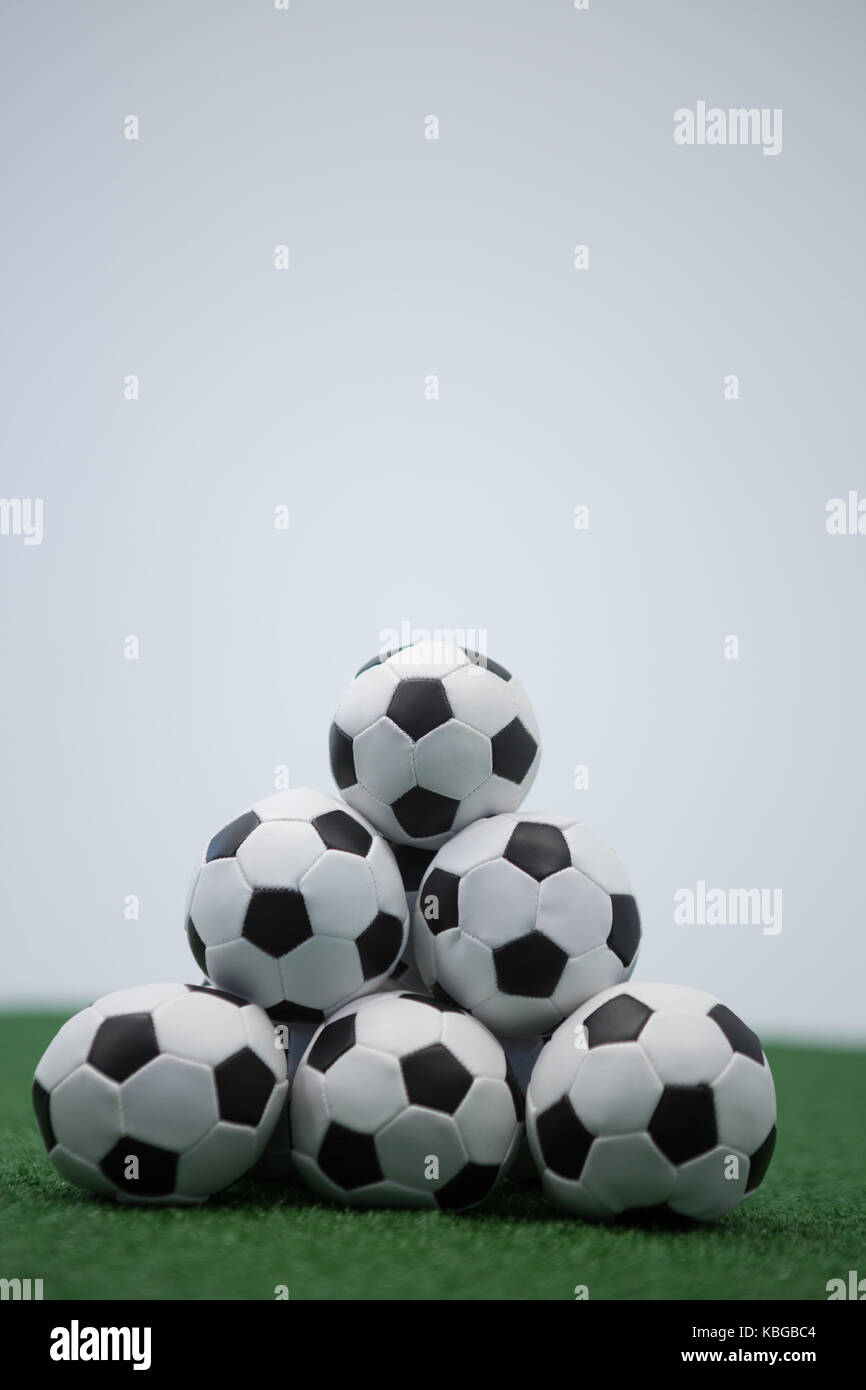 Stack of piled up football soccer balls on artificial grass against ...