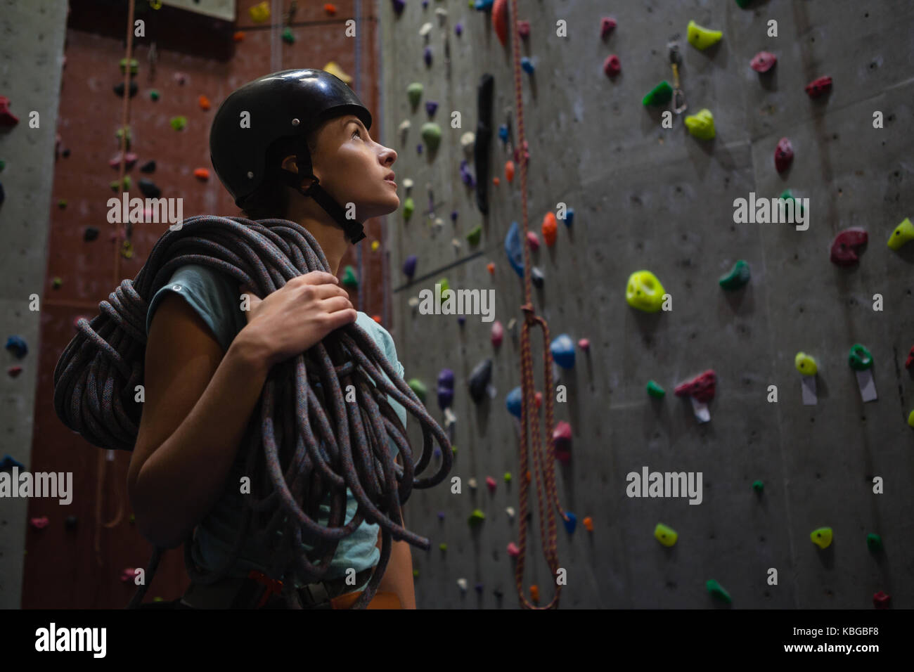 Female athlete carrying rope looking up while standing in fitness ...