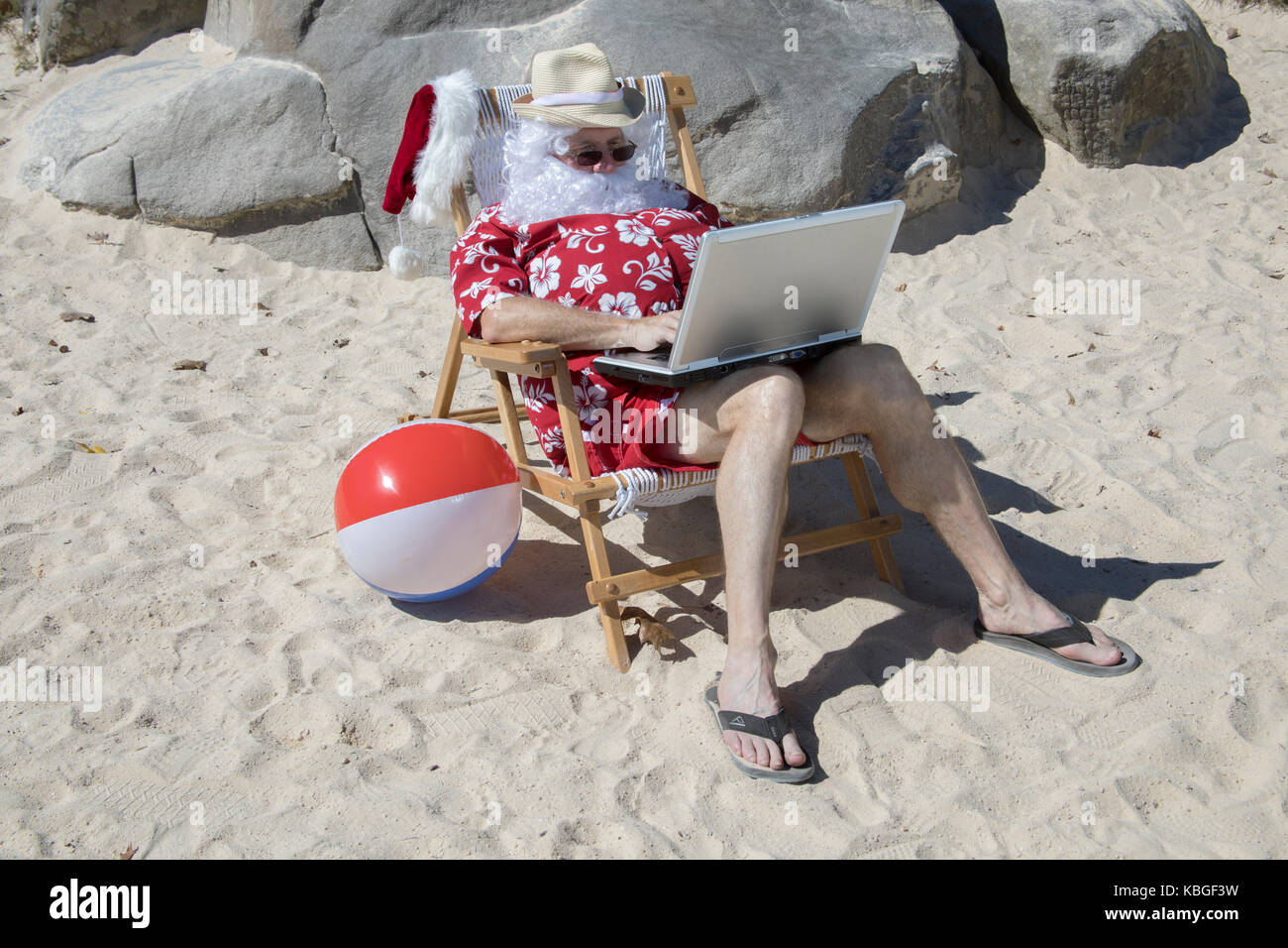 Santa Claus in red swimming trunks ans Hawaiian shirt lounging on sandy ...