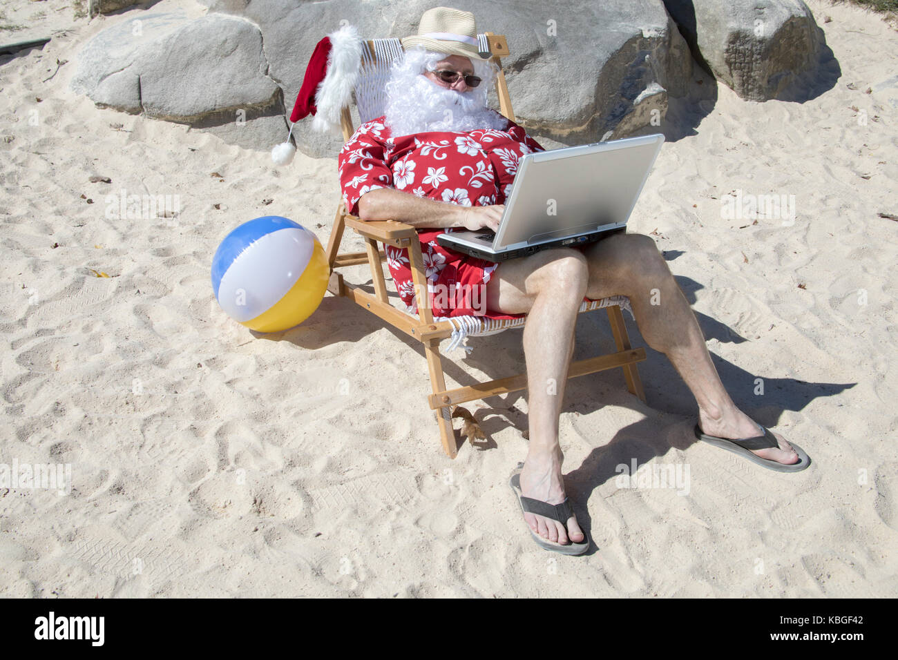 Santa Claus in red swimming trunks ans Hawaiian shirt lounging on sandy ...