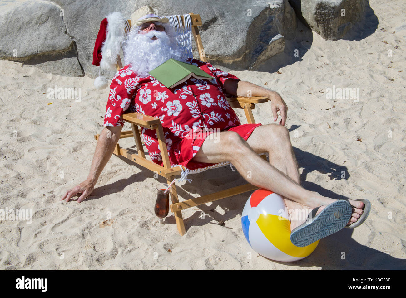 Santa Claus in red swimming trunks ans Hawaiian shirt lounging on sandy ...