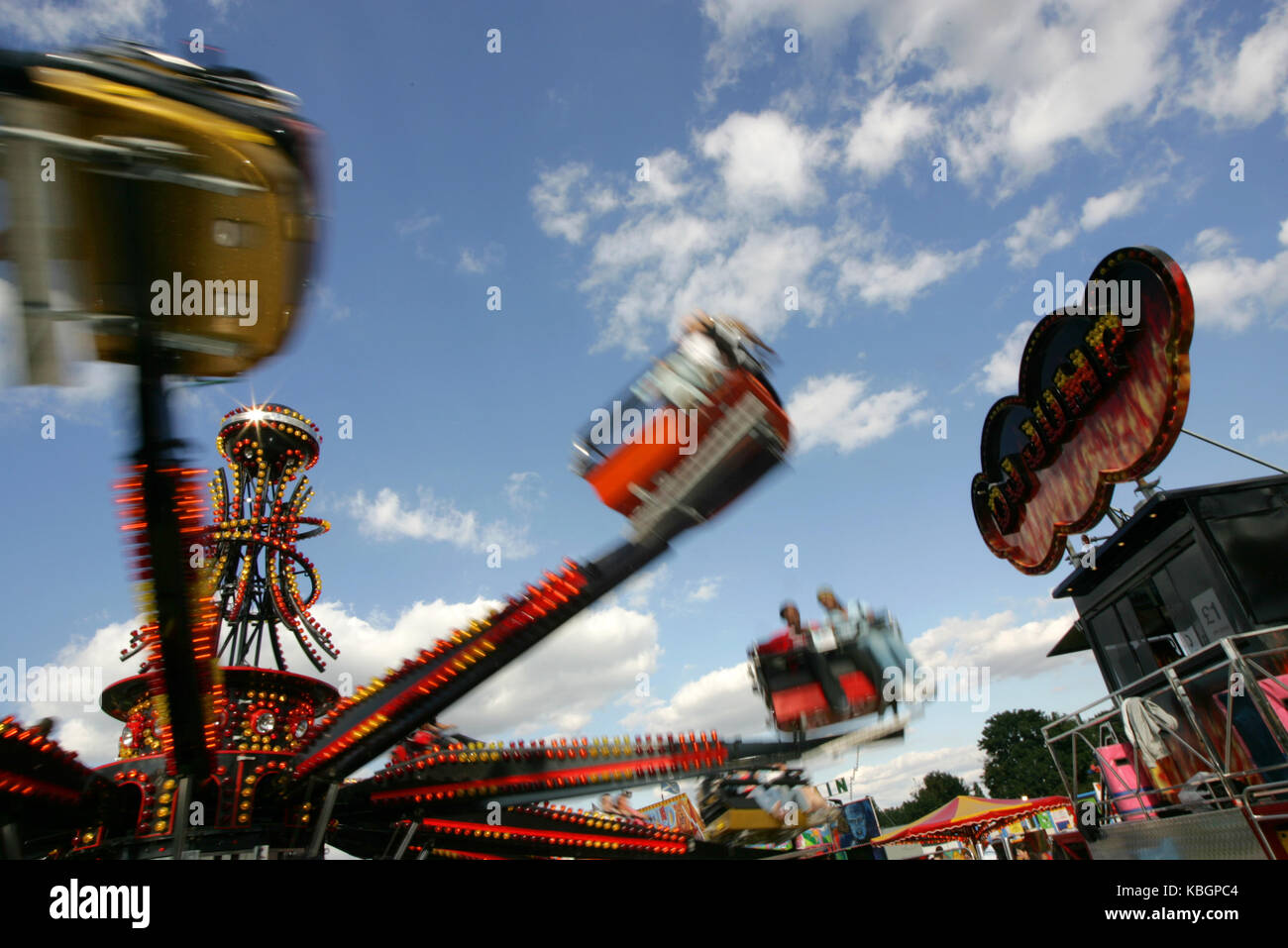 A colourful funfair ride at Birminghm carnival against a blue sky ...