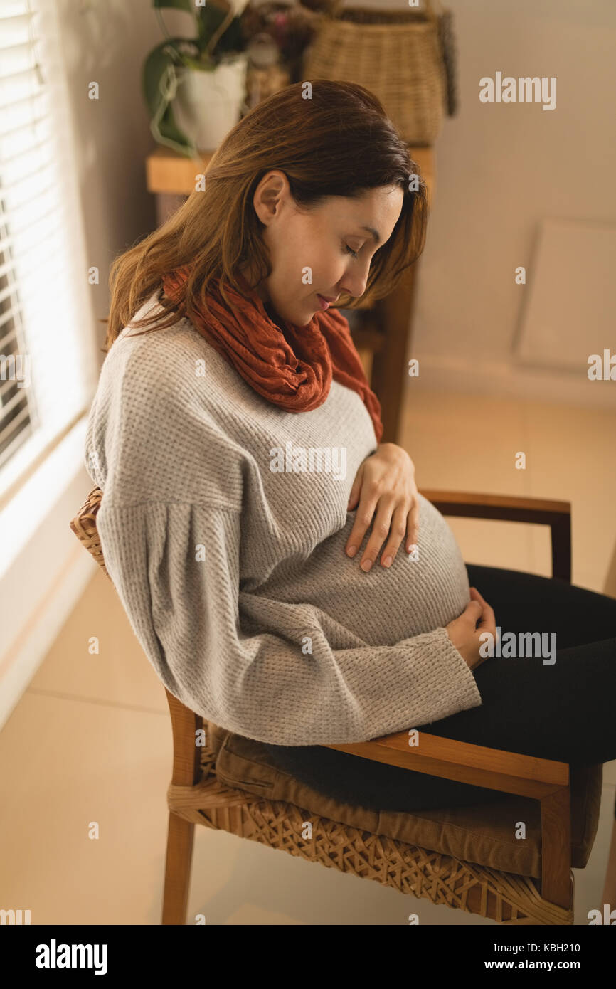 Pregnant woman sitting on a chair at home Stock Photo - Alamy