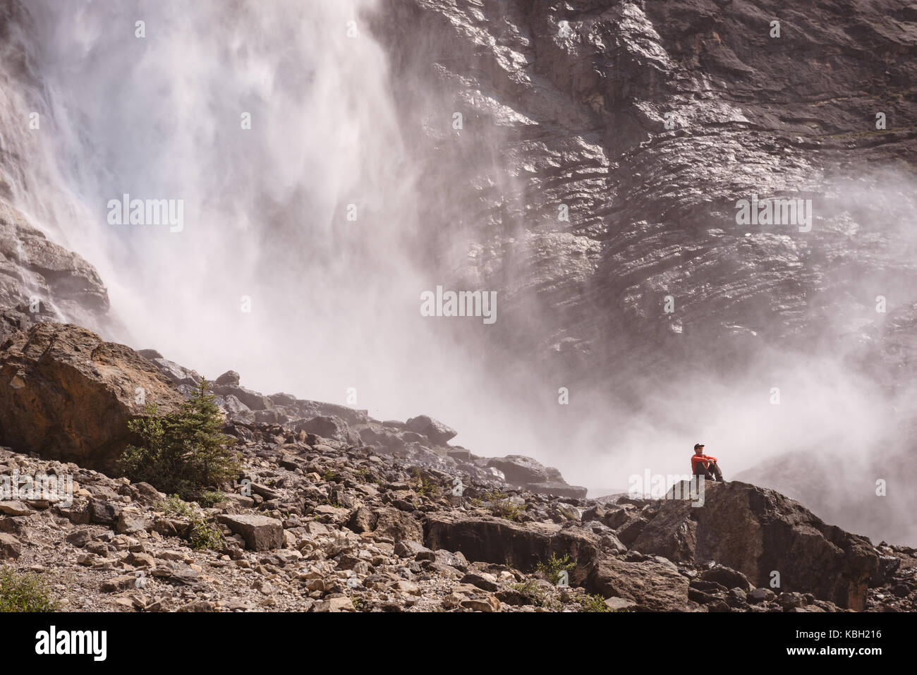 Man sitting near waterfall in countryside Stock Photo - Alamy