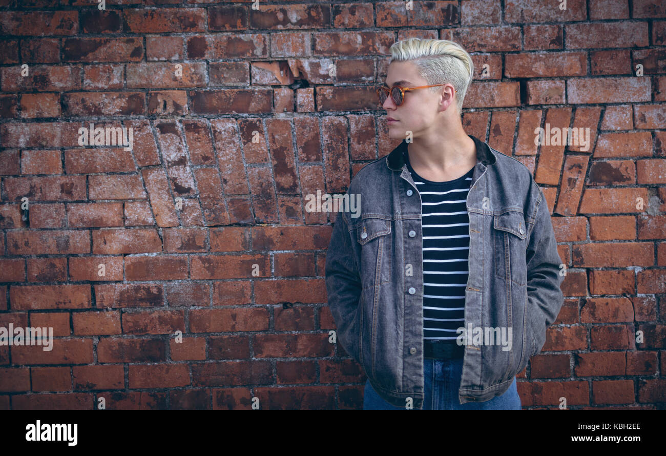 Stylish man posing against brick wall Stock Photo - Alamy