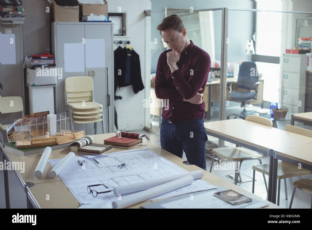 Thoughtful architect looking at blueprint in studio Stock Photo - Alamy