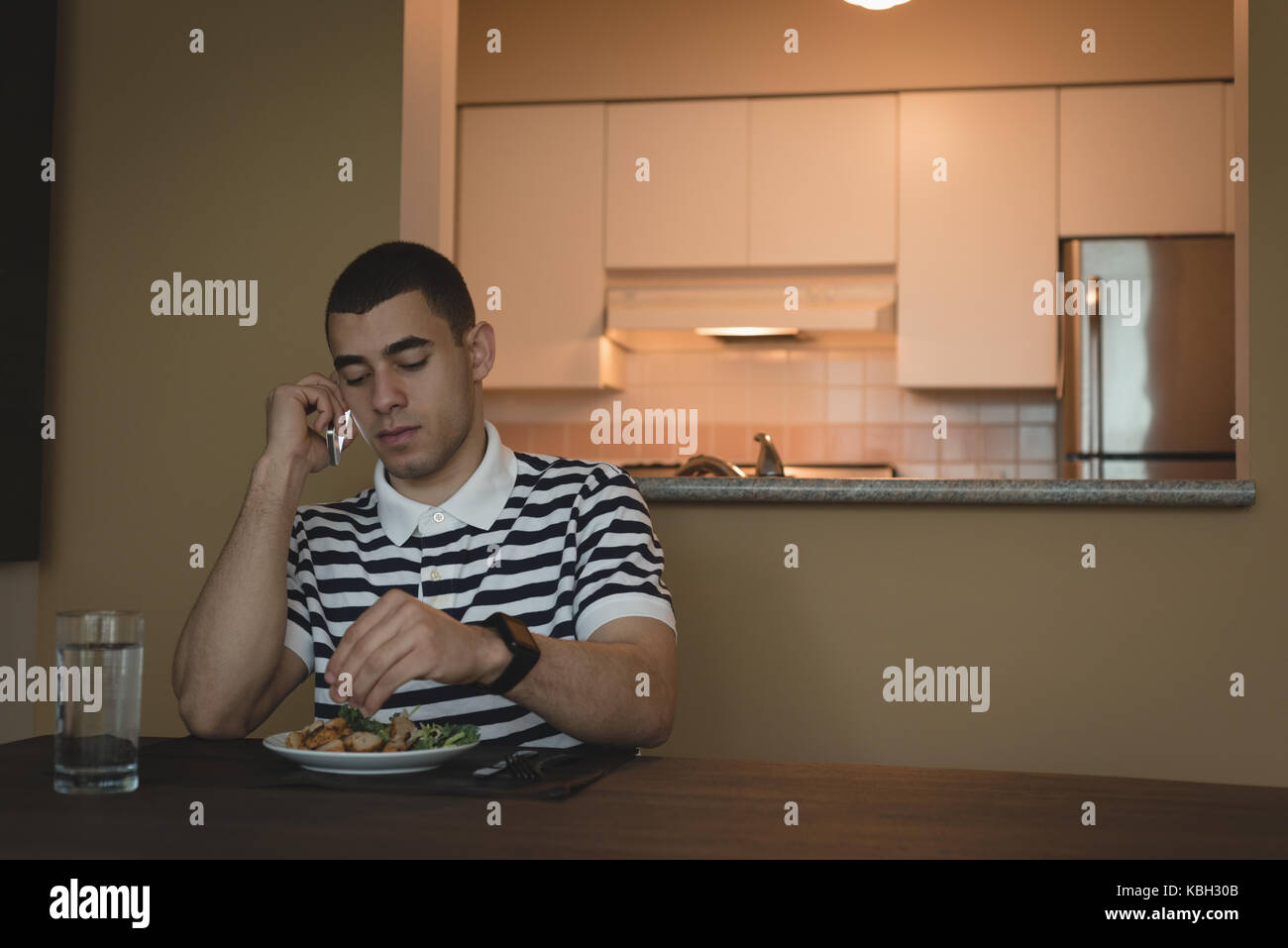 Man talking on mobile phone while having meal at home Stock Photo - Alamy