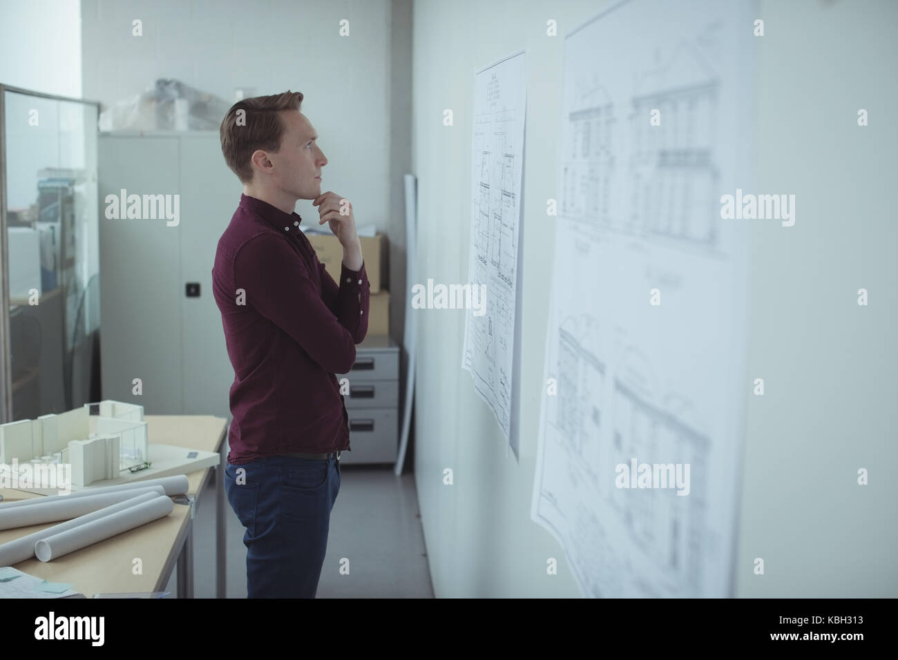Architect looking at blueprint in studio Stock Photo - Alamy