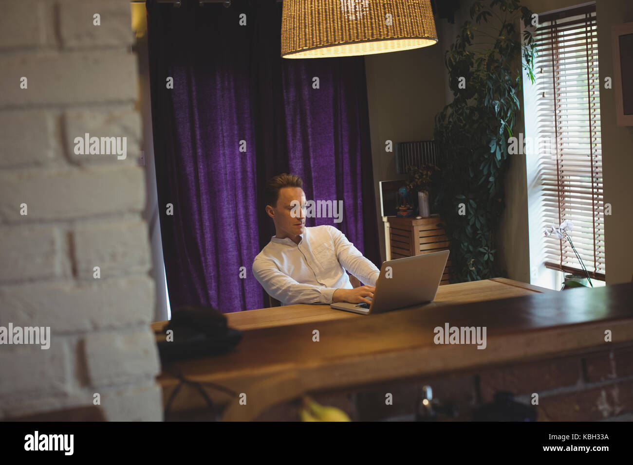 Man at desk using laptop desk in home Stock Photo - Alamy